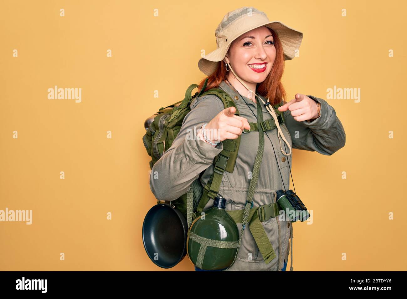 Young redhead backpacker woman hiking wearing backpack and hat over ...