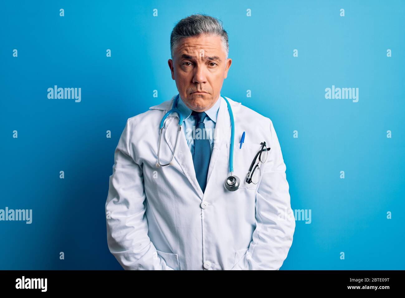 Middle age handsome grey-haired doctor man wearing coat and blue ...