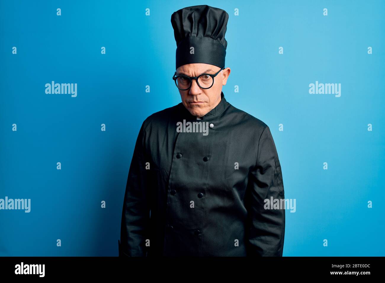 Middle age handsome grey-haired chef man wearing cooker uniform and hat ...