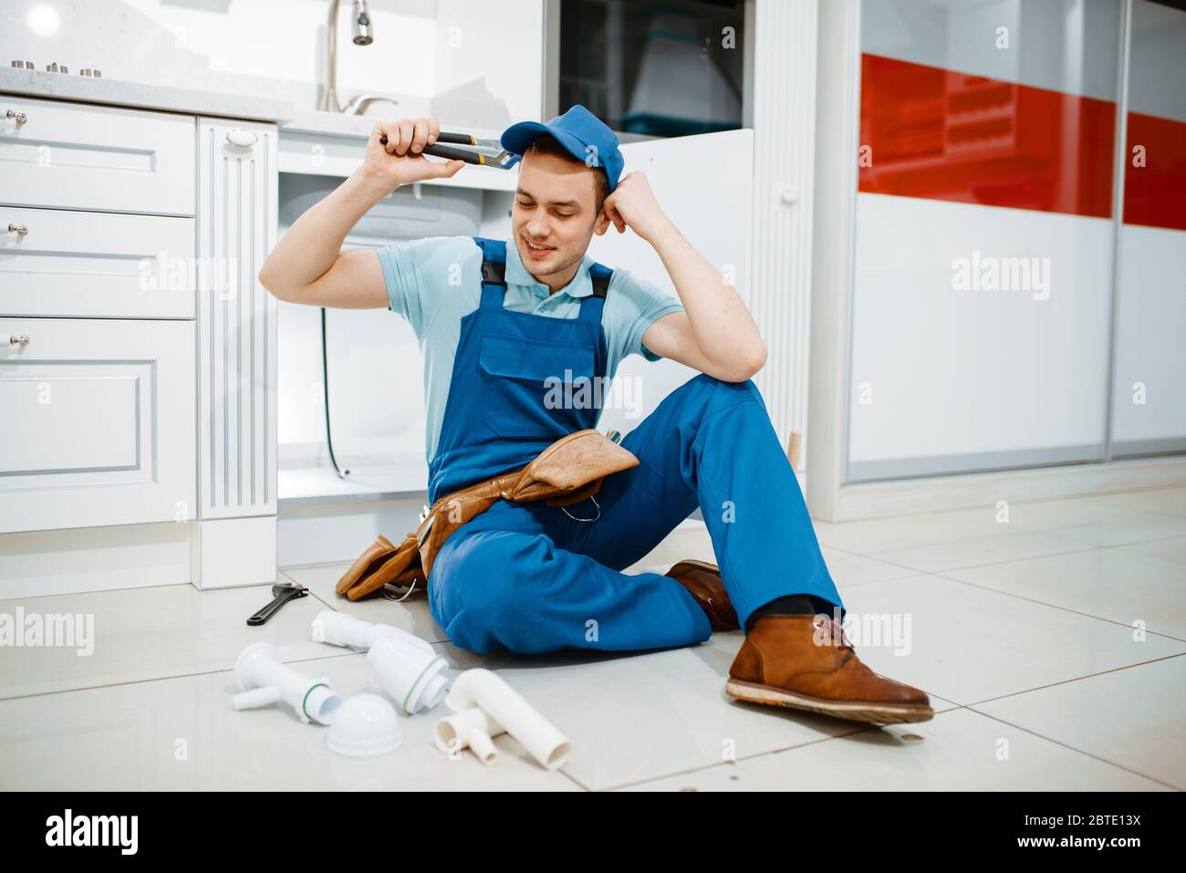Smiling male plumber in uniform holds drain pipe Stock Photo - Alamy