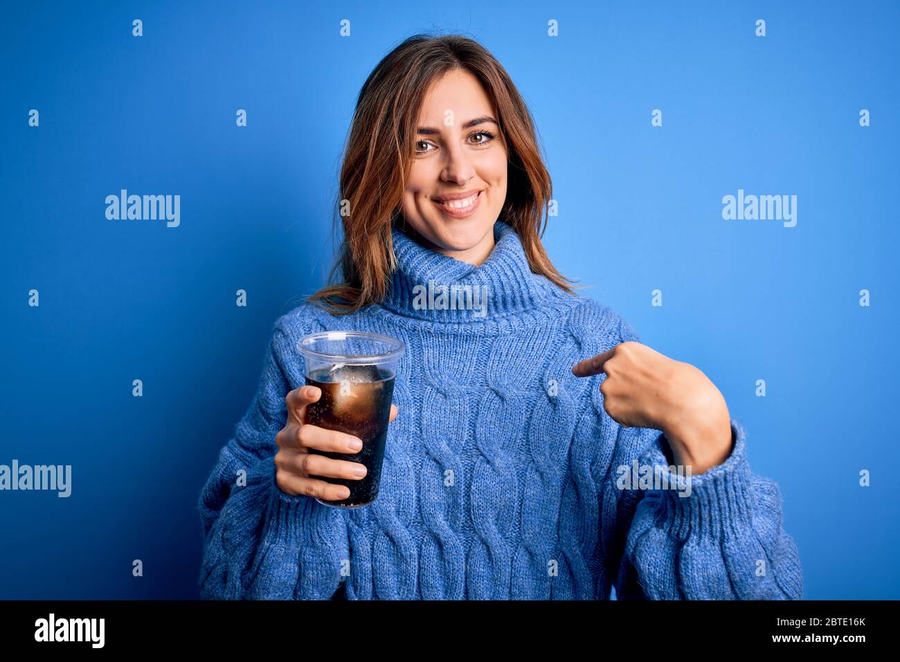Young beautiful brunette woman drinking glass with cola refreshment ...