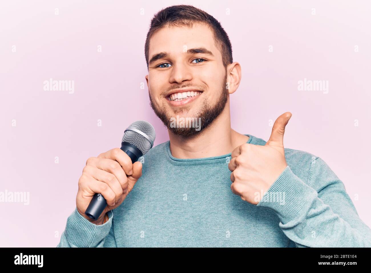 Young handsome man singing song using microphone smiling happy and ...