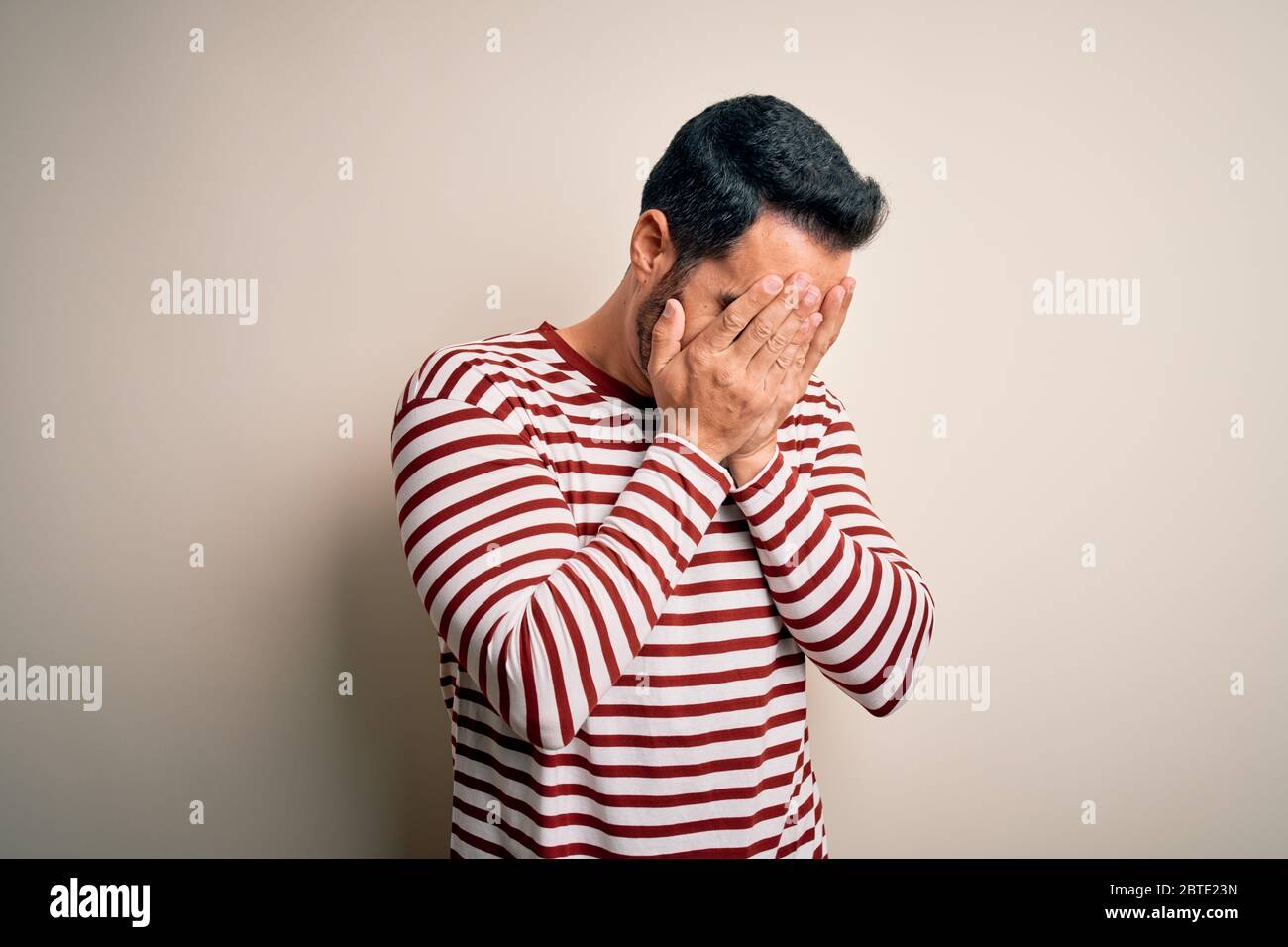 Young handsome man with beard wearing casual striped t-shirt standing ...