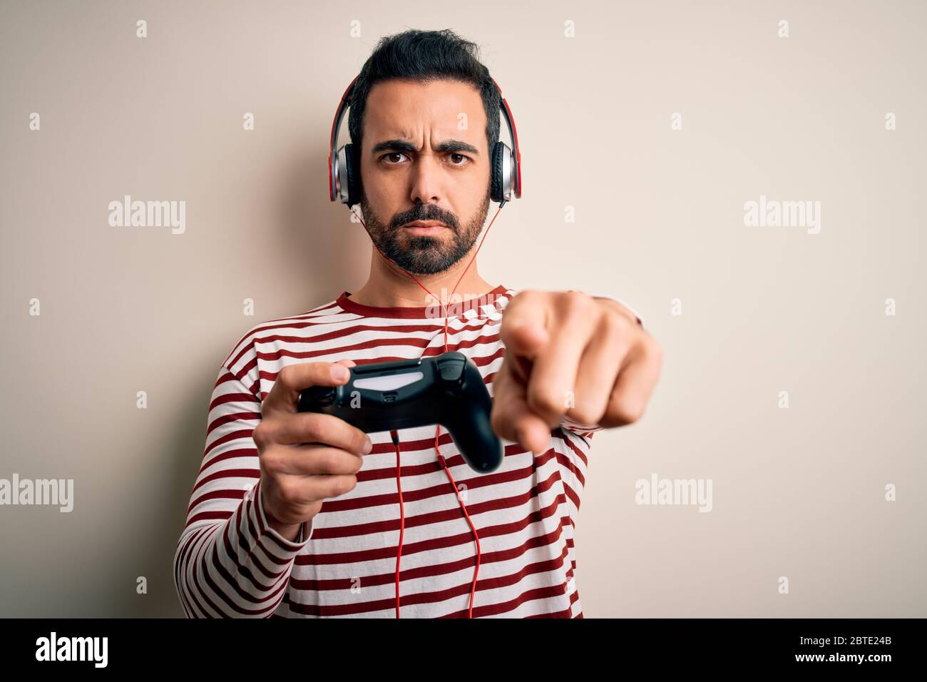 Young handsome gamer man with beard playing video game using joystick ...
