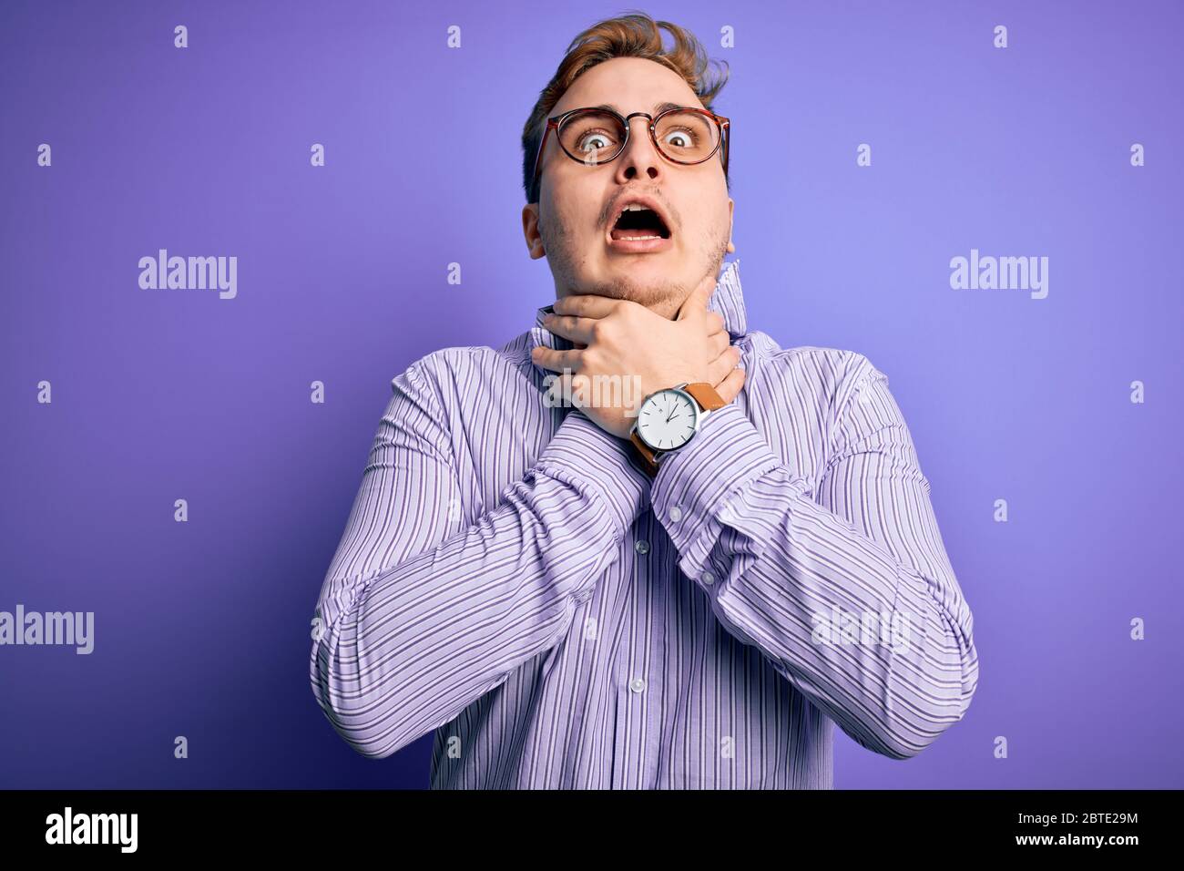 Young handsome redhead man wearing casual shirt and glasses over purple ...
