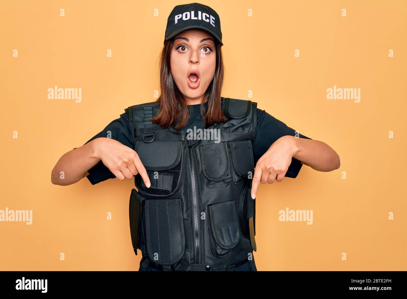 Young beautiful brunette policewoman wearing police uniform bulletproof ...