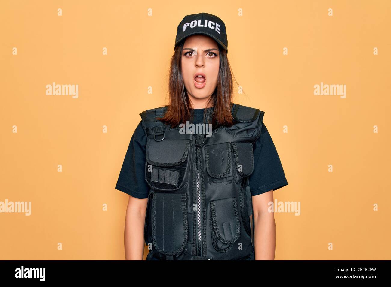 Young beautiful brunette policewoman wearing police uniform bulletproof ...