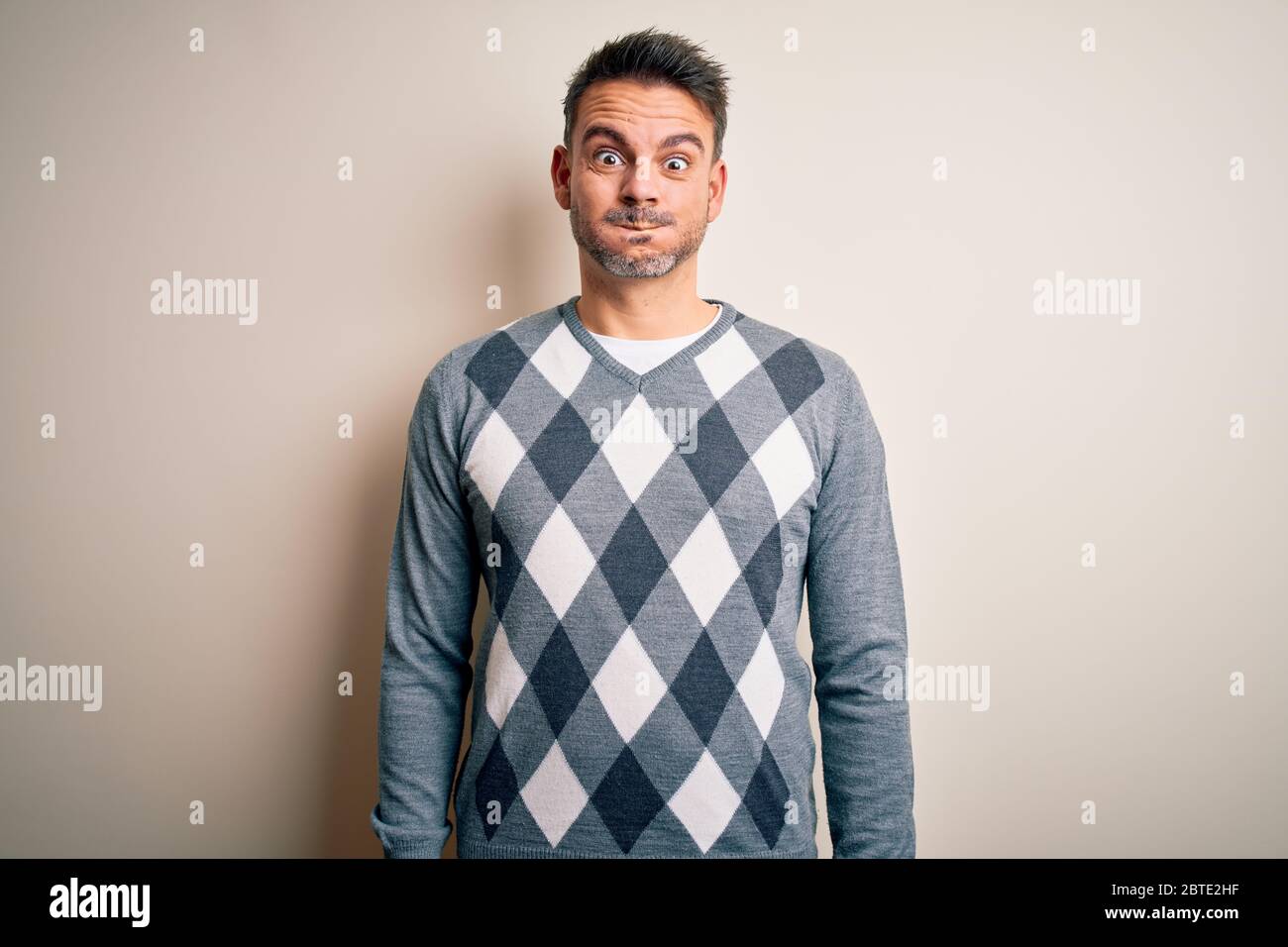 Young handsome man wearing casual sweater standing over isolated white ...