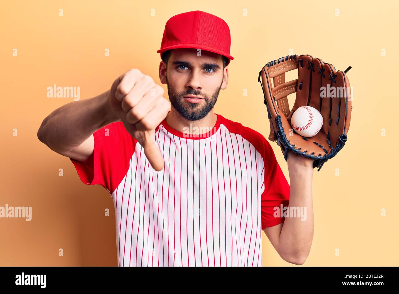 Young handsome man with beard playing baseball using ball and glove ...