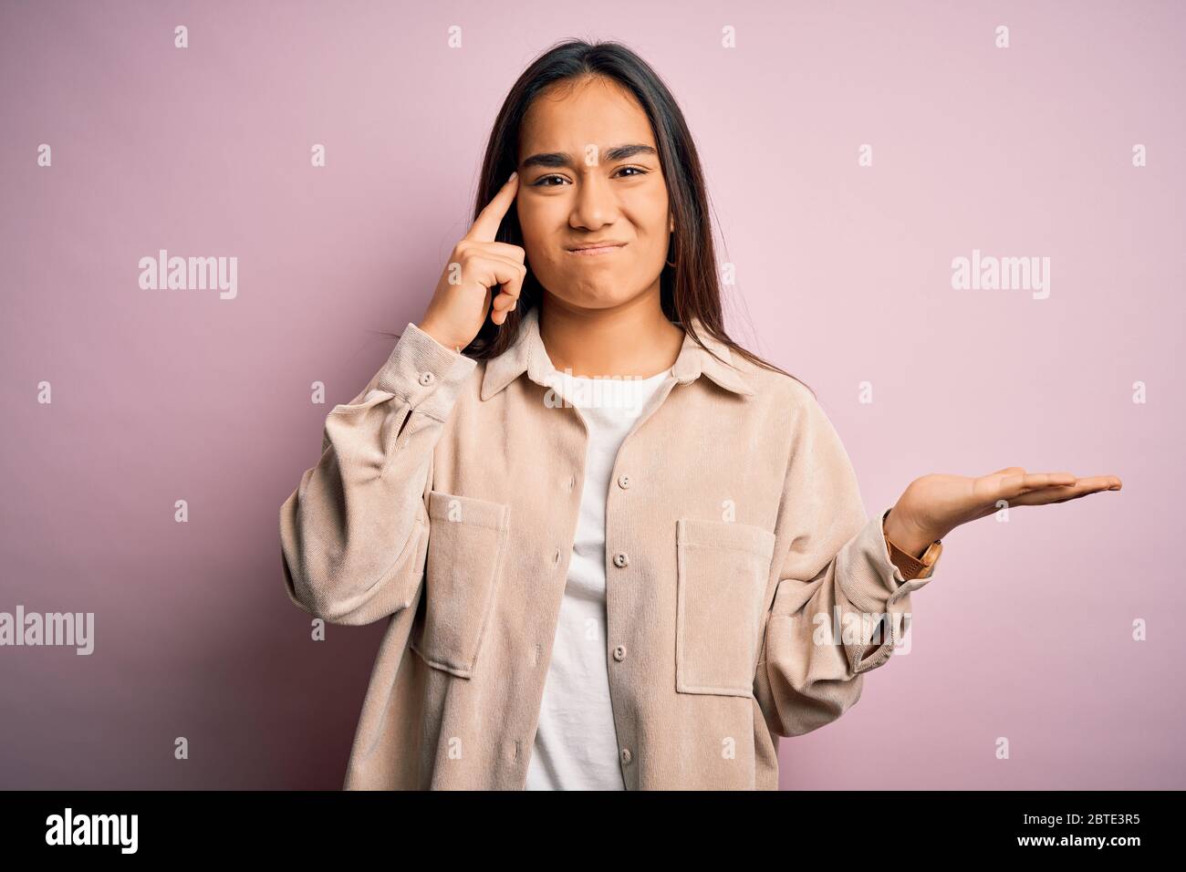 Young beautiful asian woman wearing casual shirt standing over pink ...