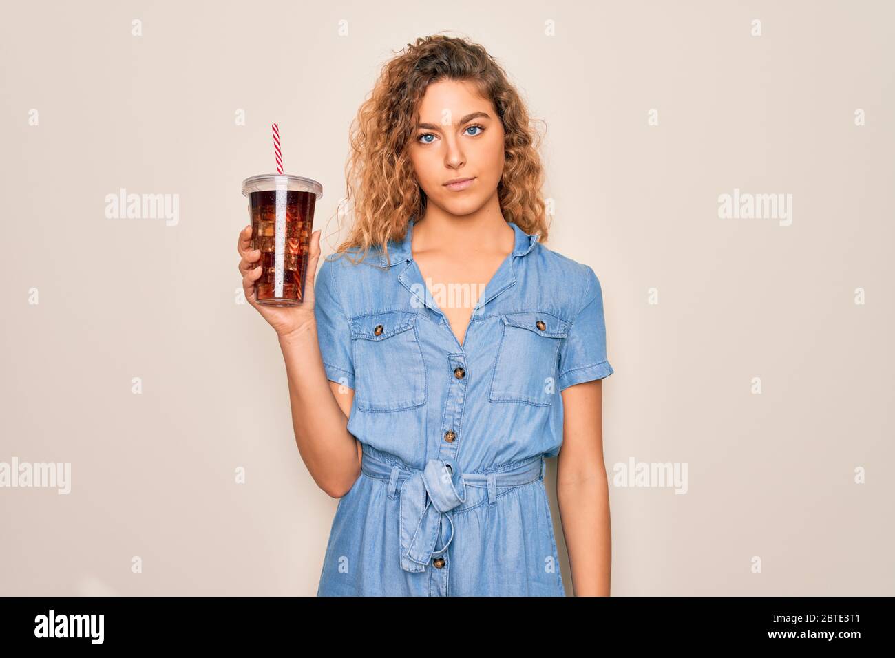 Beautiful blonde woman with blue eyes drinking cola beverage using ...