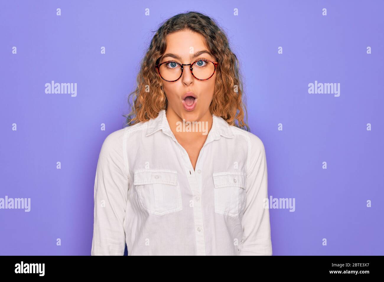 Young beautiful woman with blue eyes wearing casual shirt and glasses ...