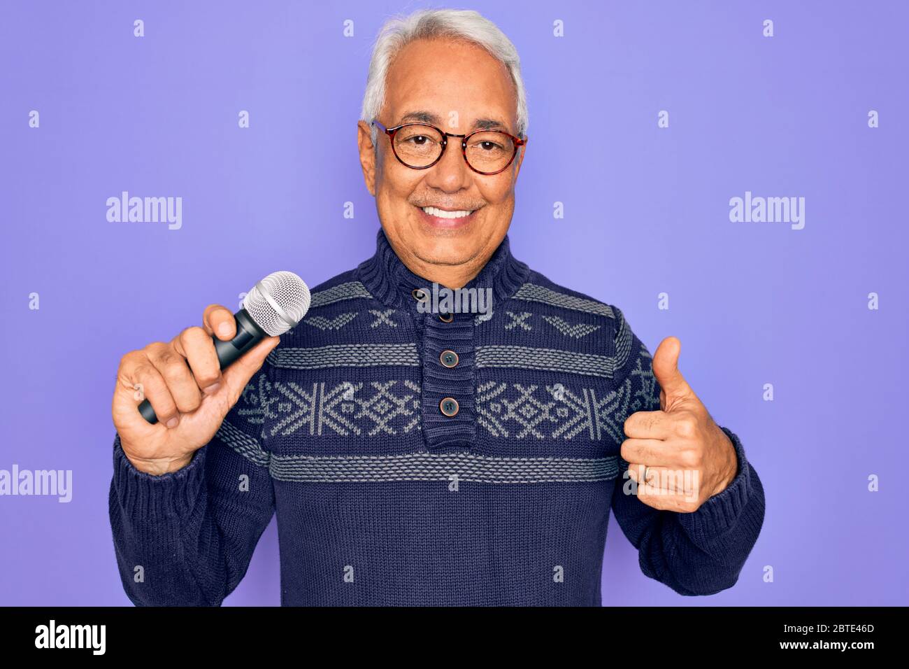 Middle age senior grey-haired singer man singing using music microphone ...