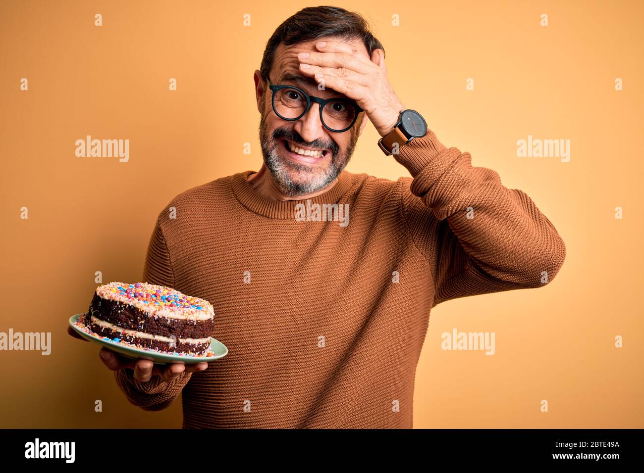 Middle age hoary man holding birthday cake standing over isolated ...