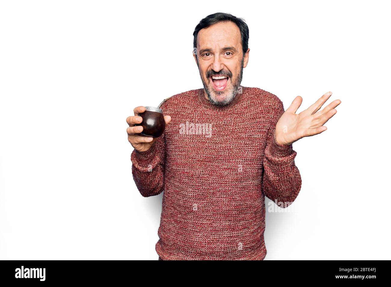 Middle age handsome man drinking cup of mate tea over isolated white ...