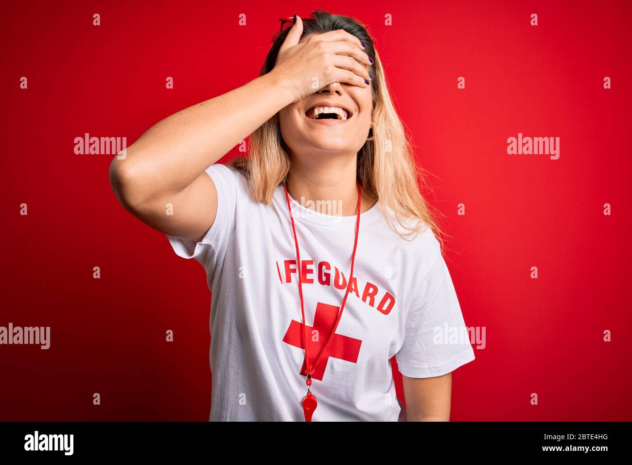 Young beautiful blonde lifeguard woman wearing t-shirt with red cross ...