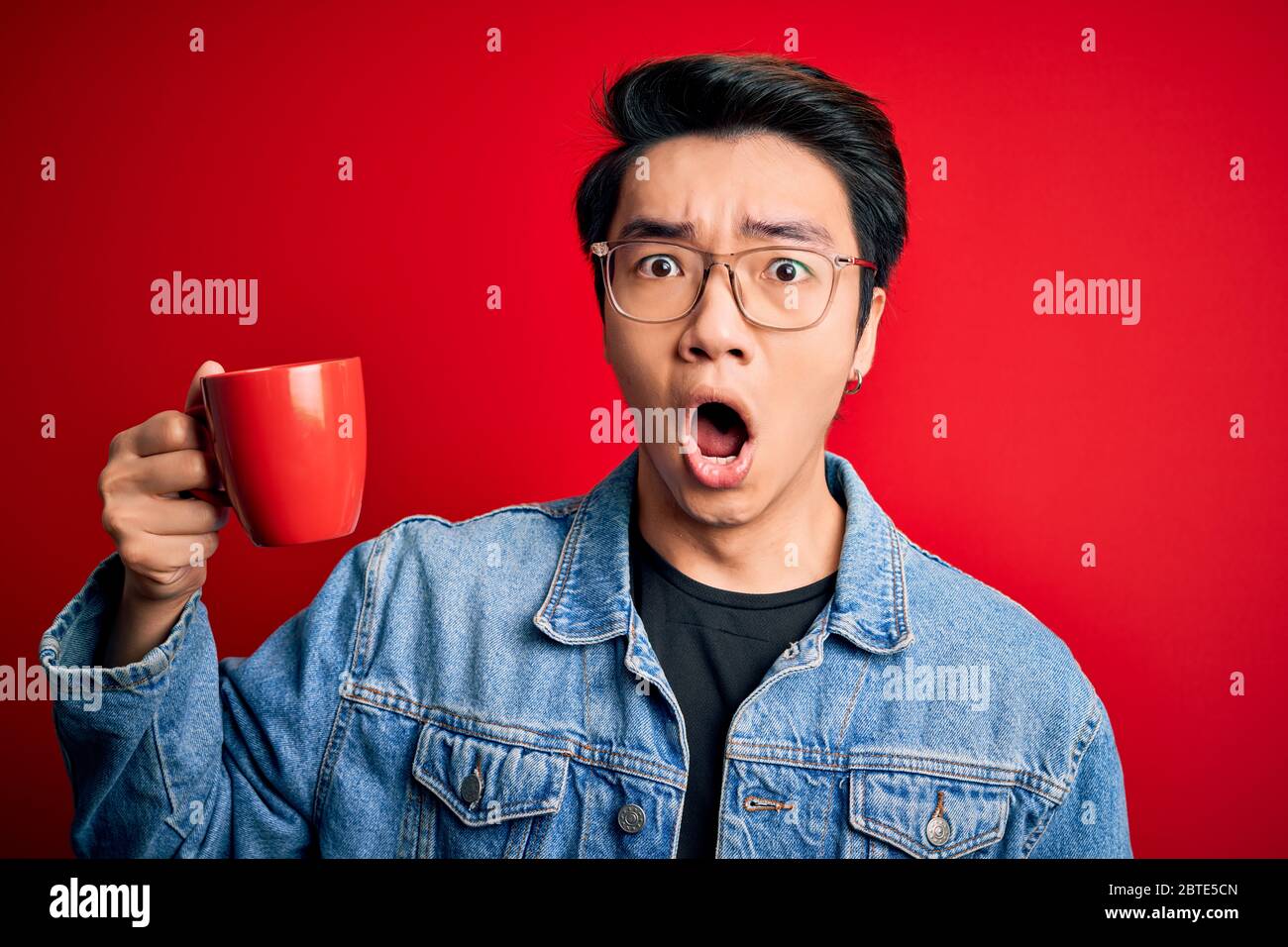 Young handsome chinese man drinking cup of coffee over isolated red ...