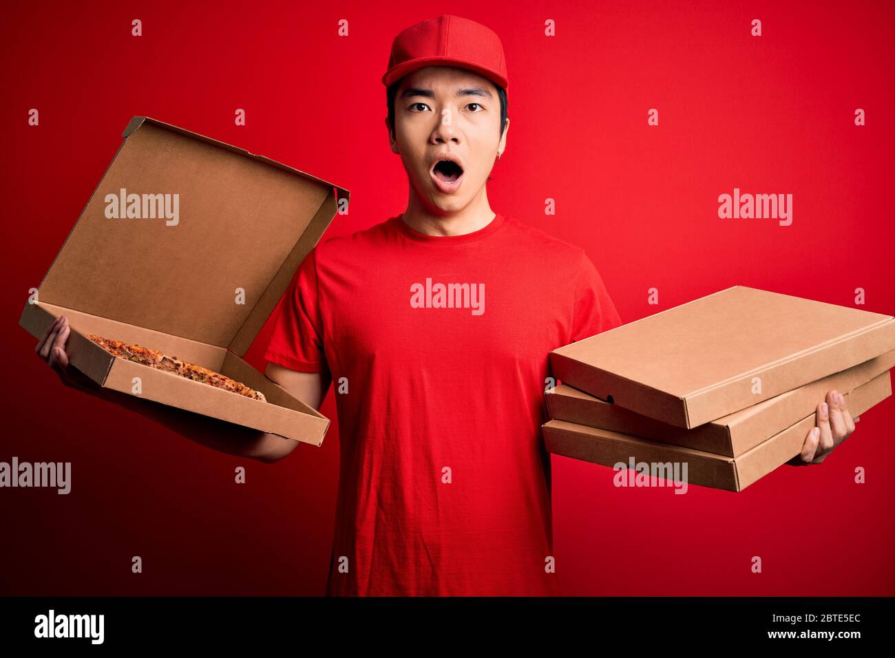 Young handsome chinese delivery man holding deliver boxes with Italian ...