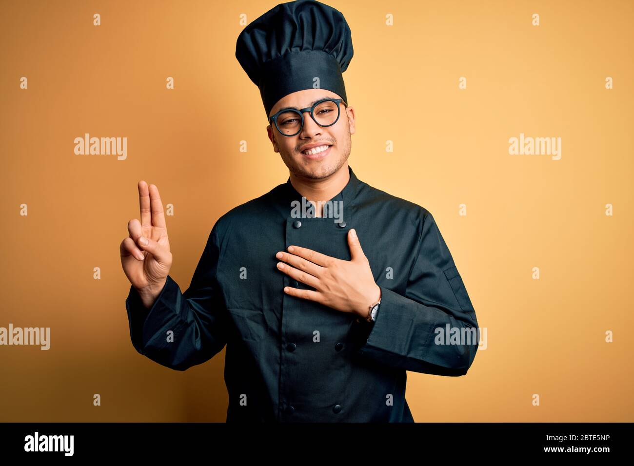 Young brazilian chef man wearing cooker uniform and hat over isolated ...