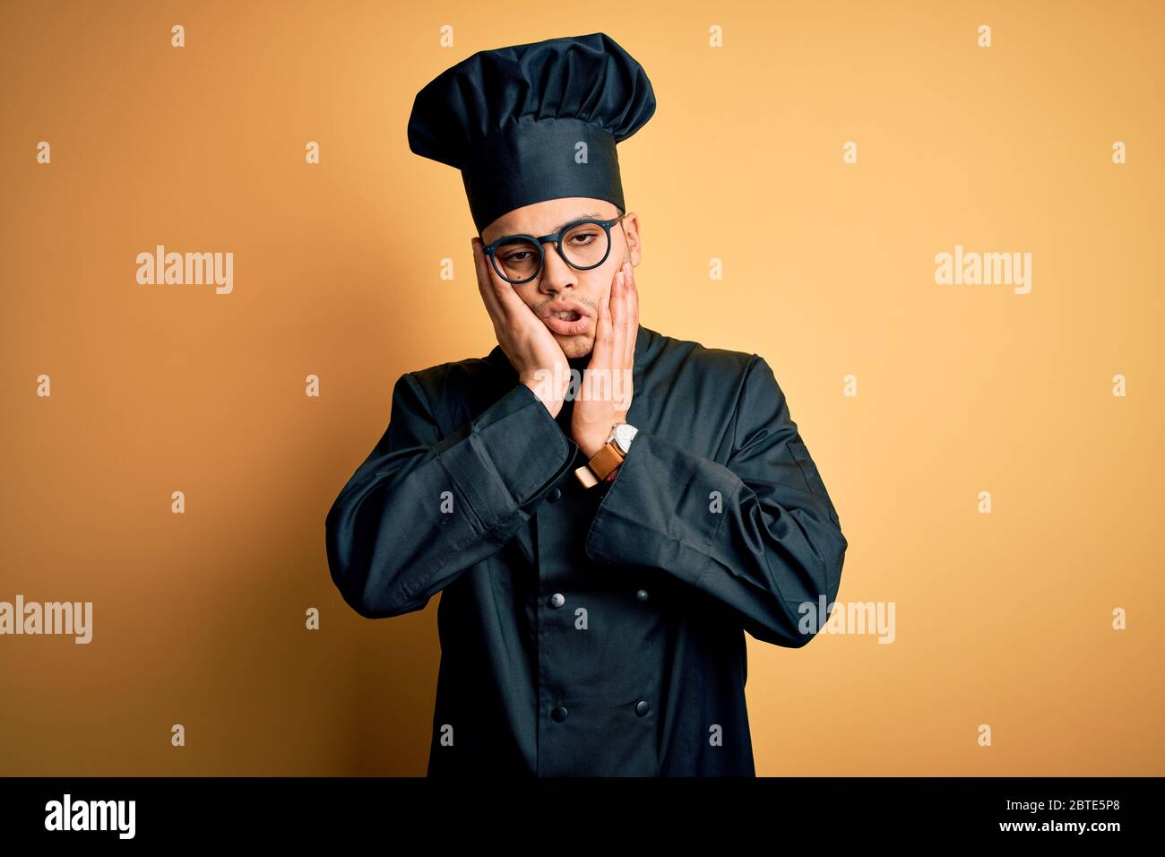 Young brazilian chef man wearing cooker uniform and hat over isolated ...