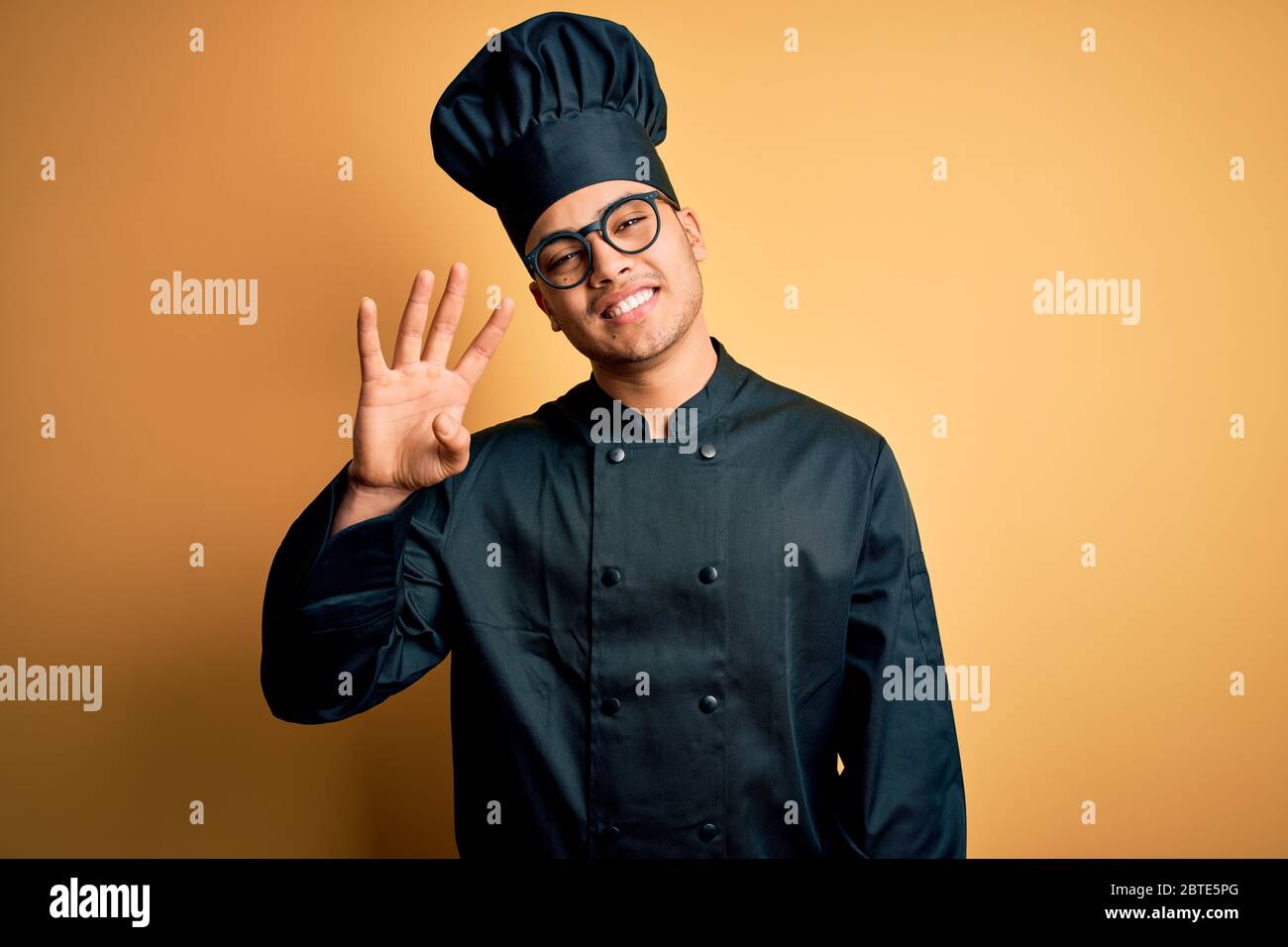 Young brazilian chef man wearing cooker uniform and hat over isolated ...