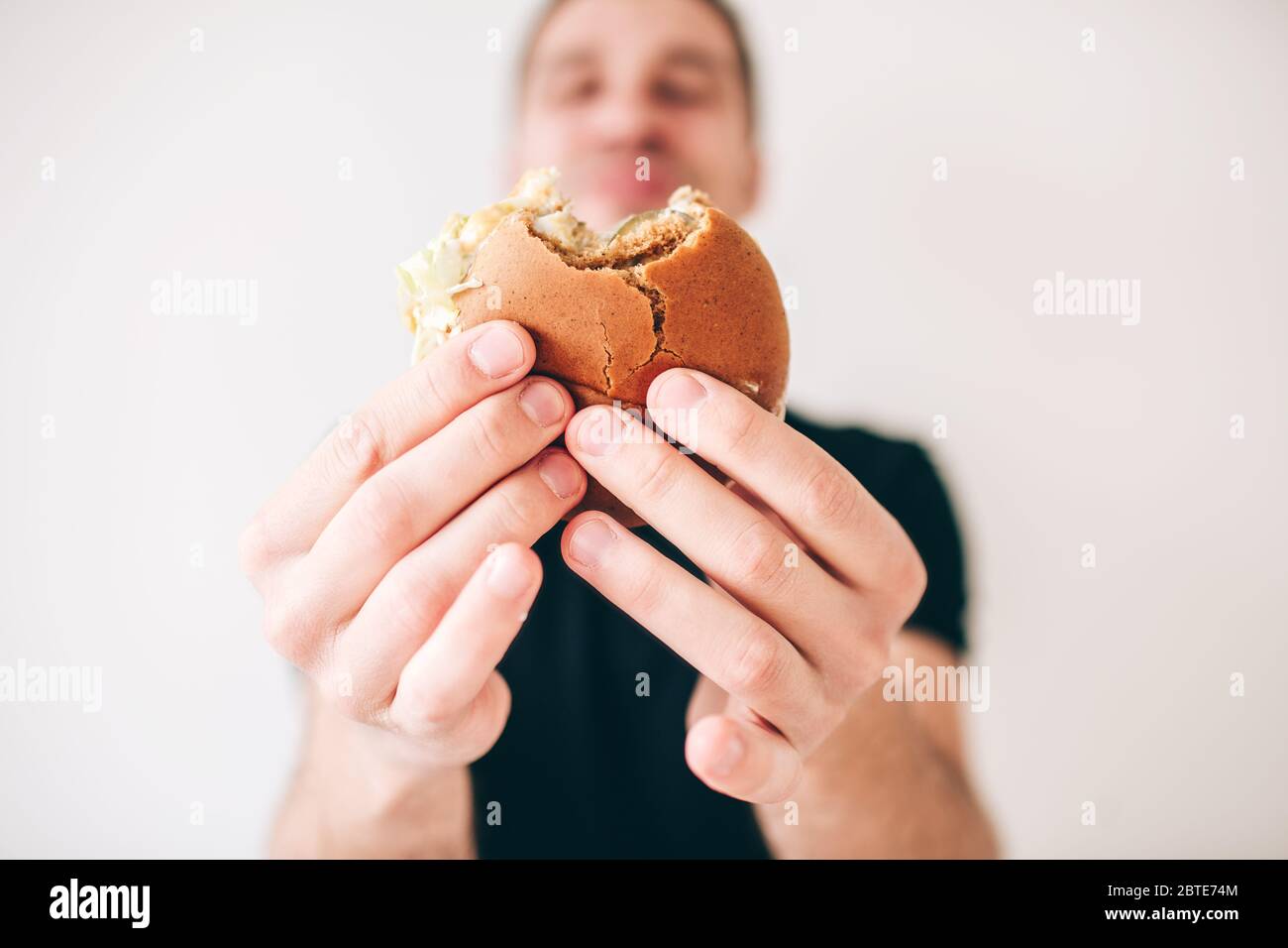 Young man isolated over white background. Guy hold bited cheeseburger ...