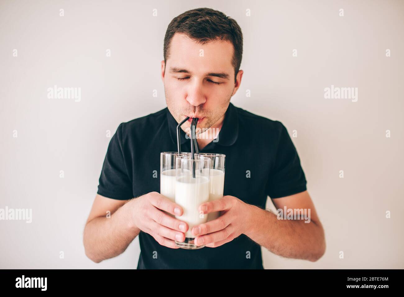 Young man isolated over white background. Guy hold three glasses with ...