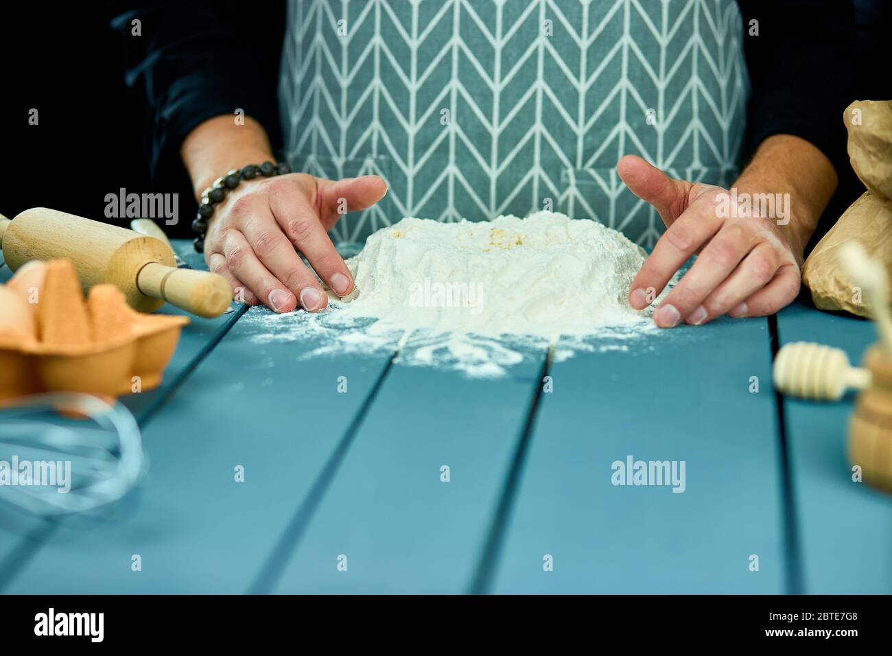 Man forming the dough on a floured surface and kneading it with his ...