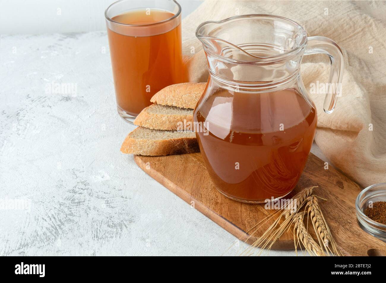 Cold kvass in a jug on a light table. Fermented bread drink. Copy space ...