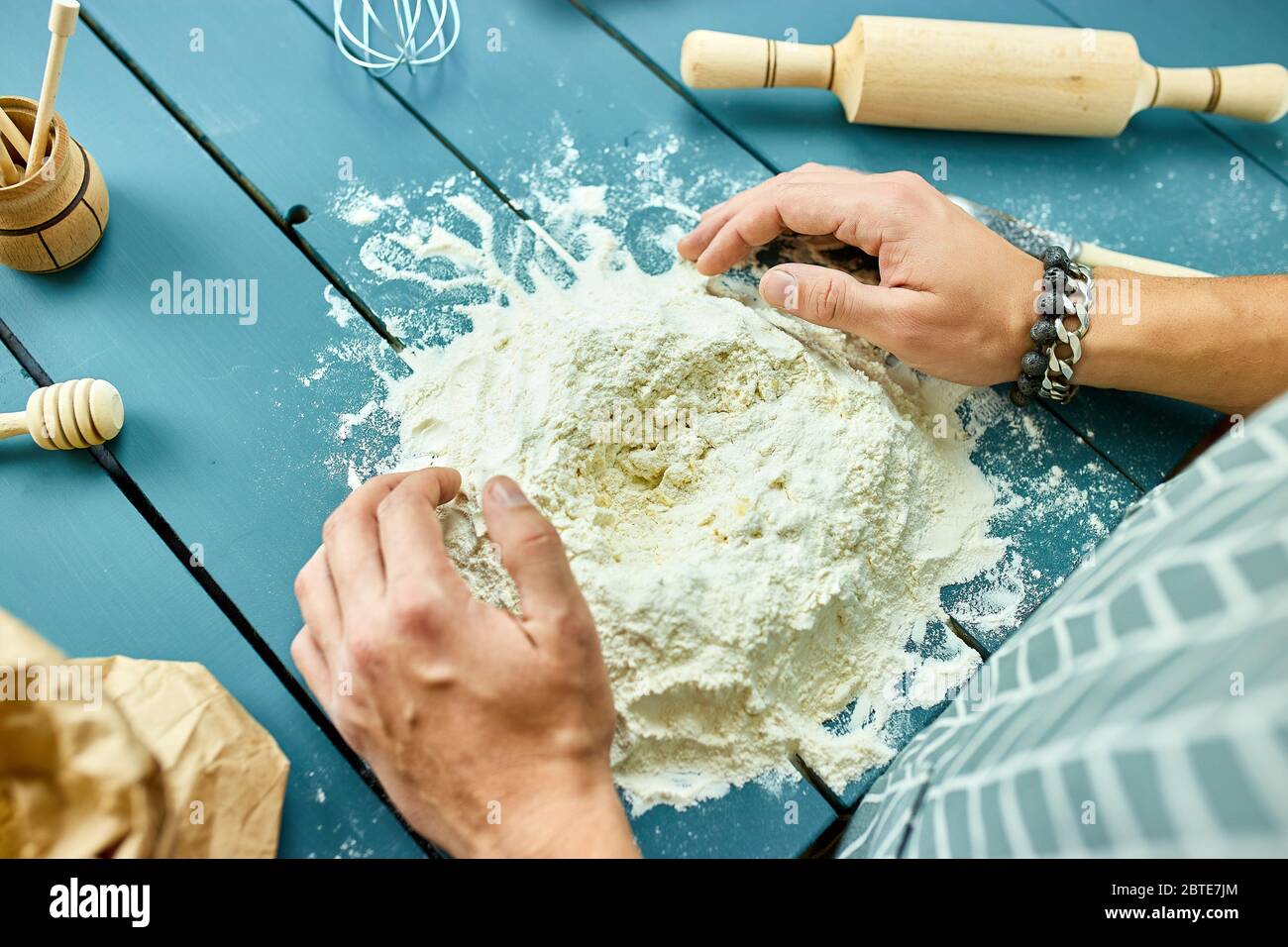 Man forming the dough on a floured surface and kneading it with his ...