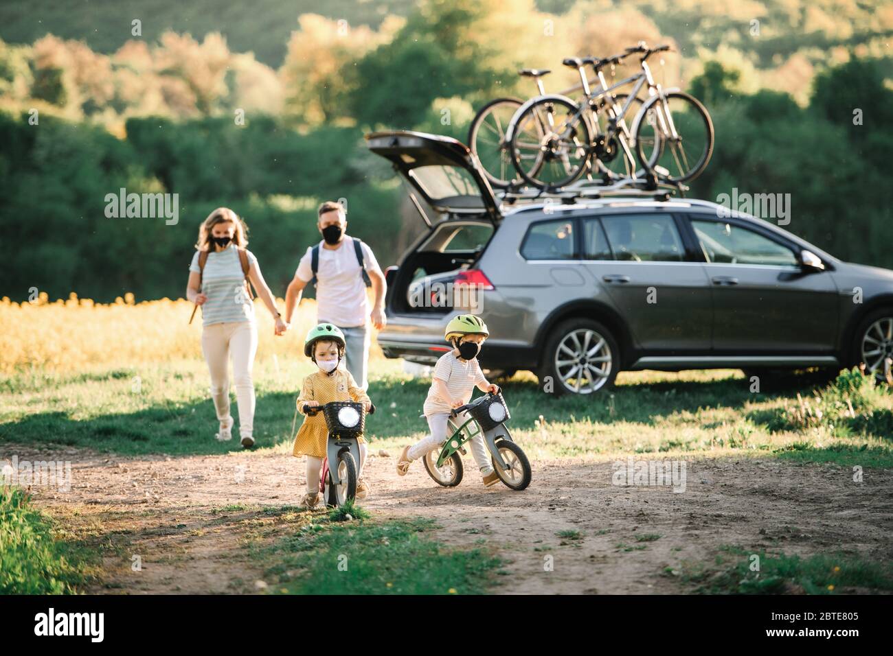 Family with two small children and face masks going on cycling trip in ...