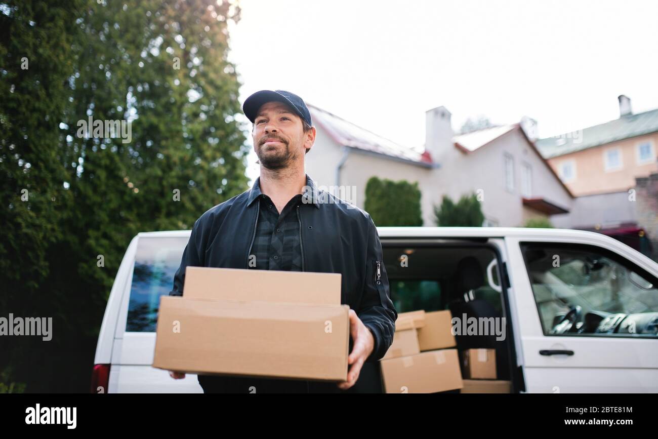 Portrait of delivery man courier delivering parcel box in town Stock ...
