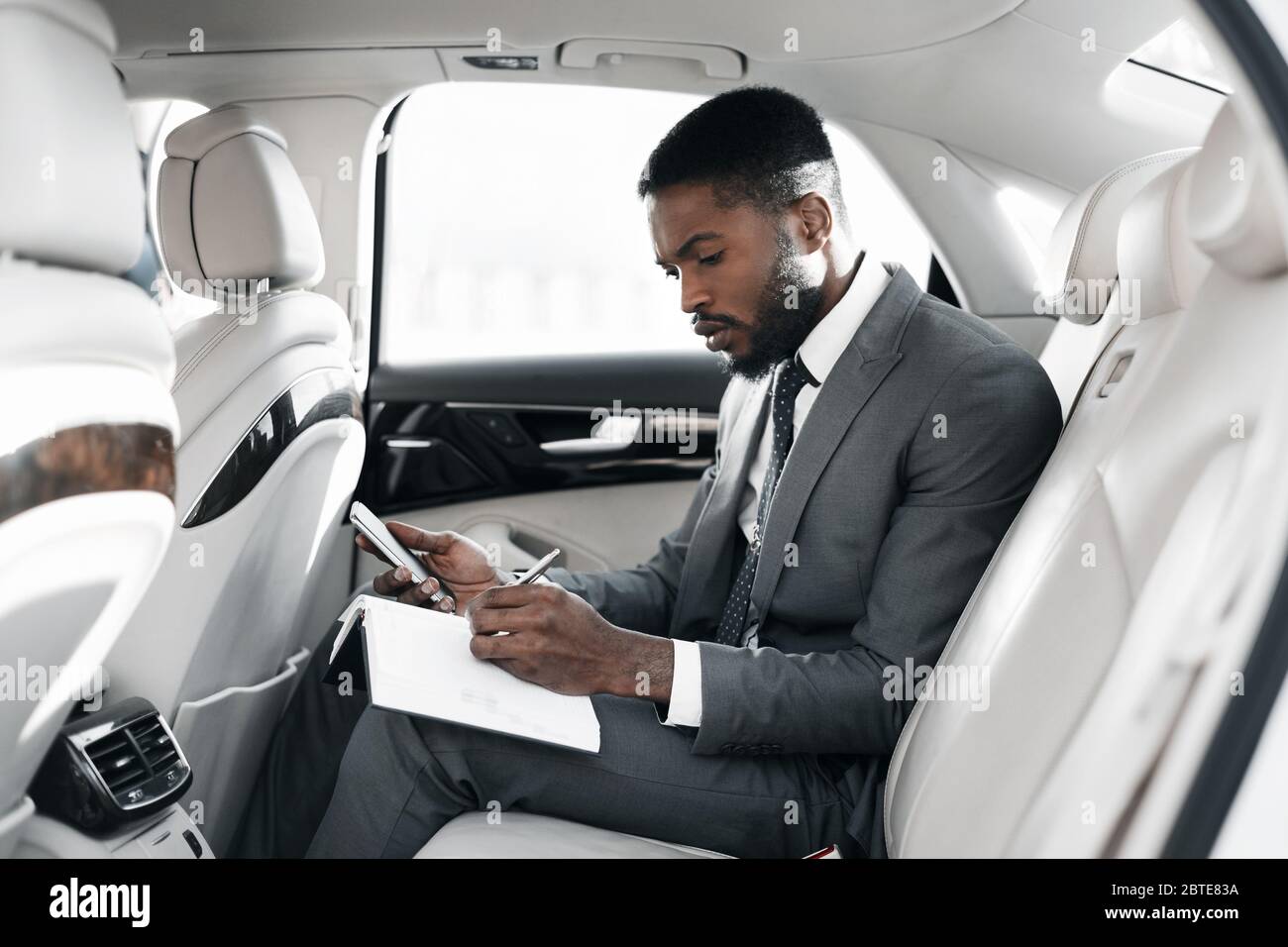 Busy Businessman Working Using Smartphone Taking Notes Sitting In Car ...