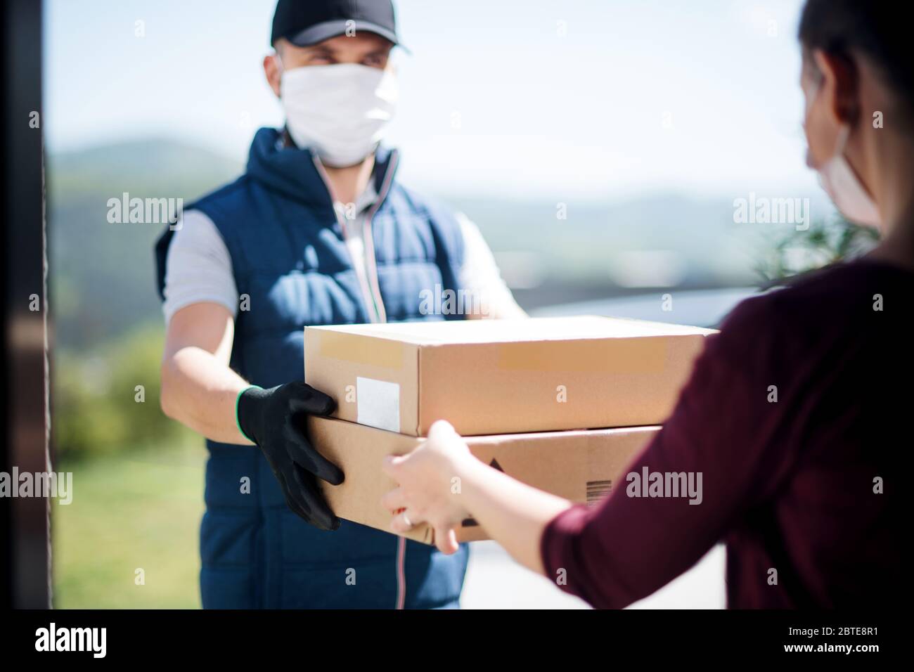 Courier with face mask delivering parcel, corona virus and quarantine ...