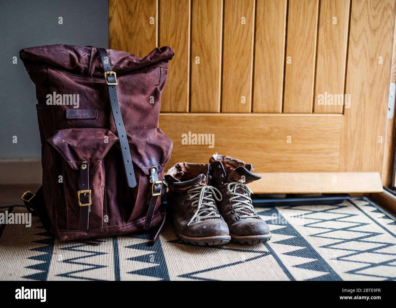 Pair of boots and backpack by open front door Stock Photo - Alamy