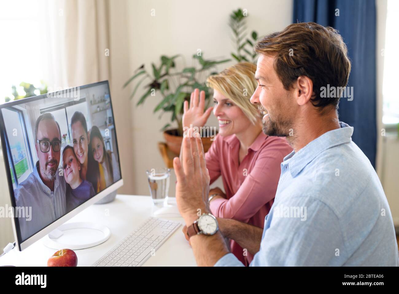 Happy couple having video call with friends on computer indoors at home ...