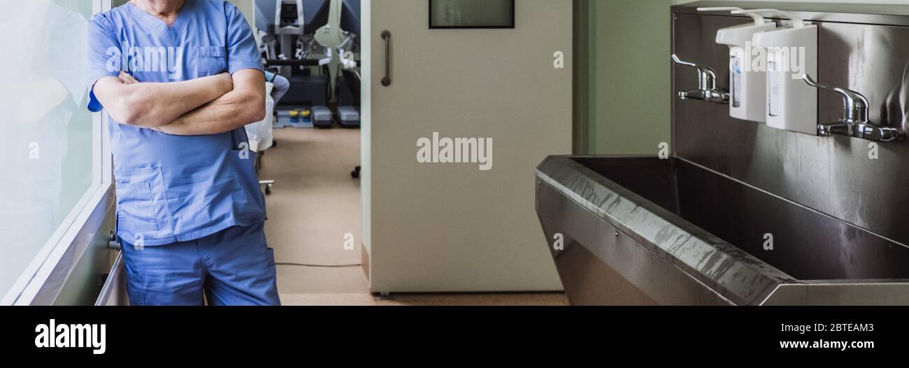 Crossed arms on the chest of a doctor standing at the window in the ...