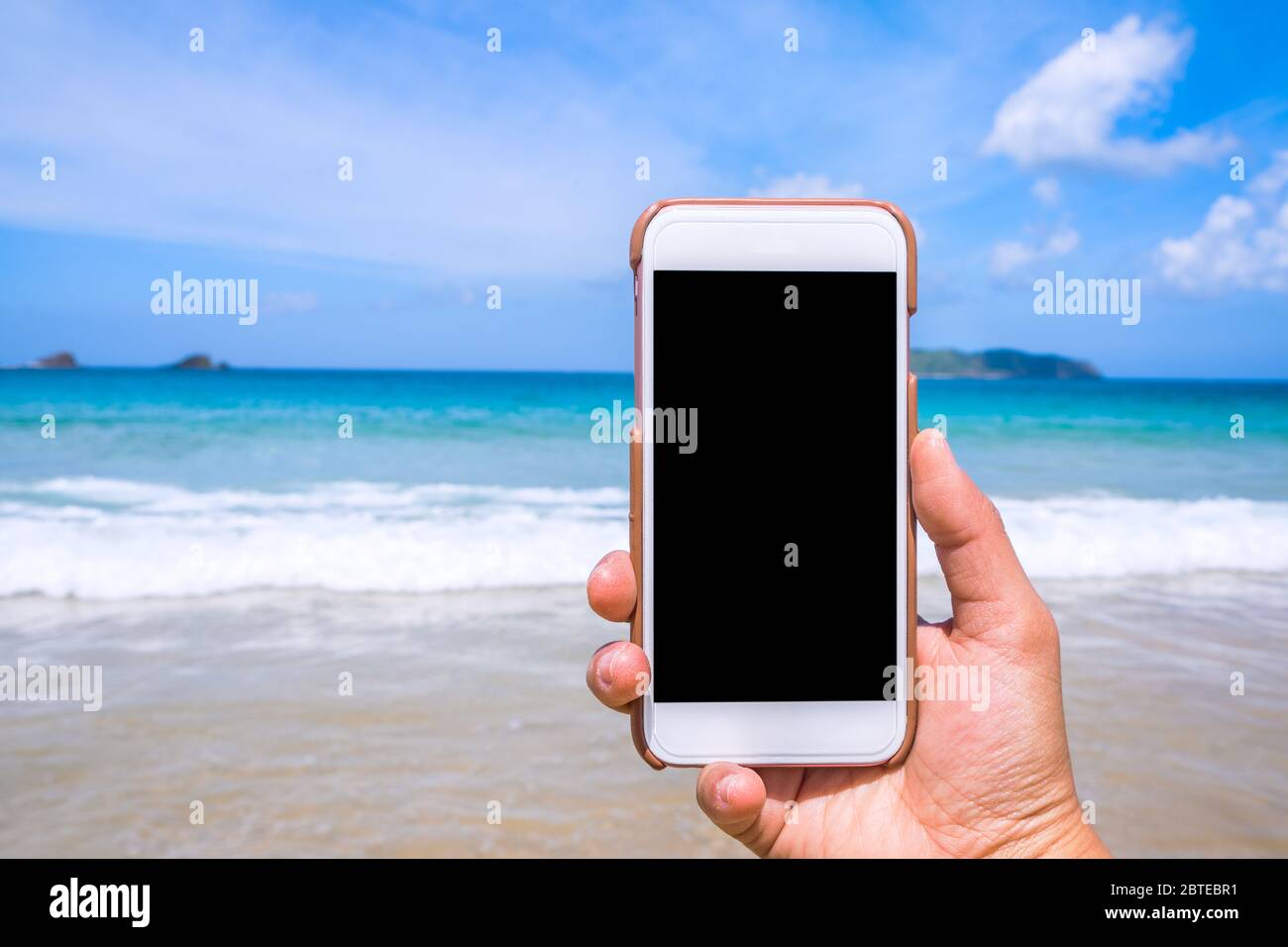 Tourist using phone at the beach with the sea, hand holding white ...