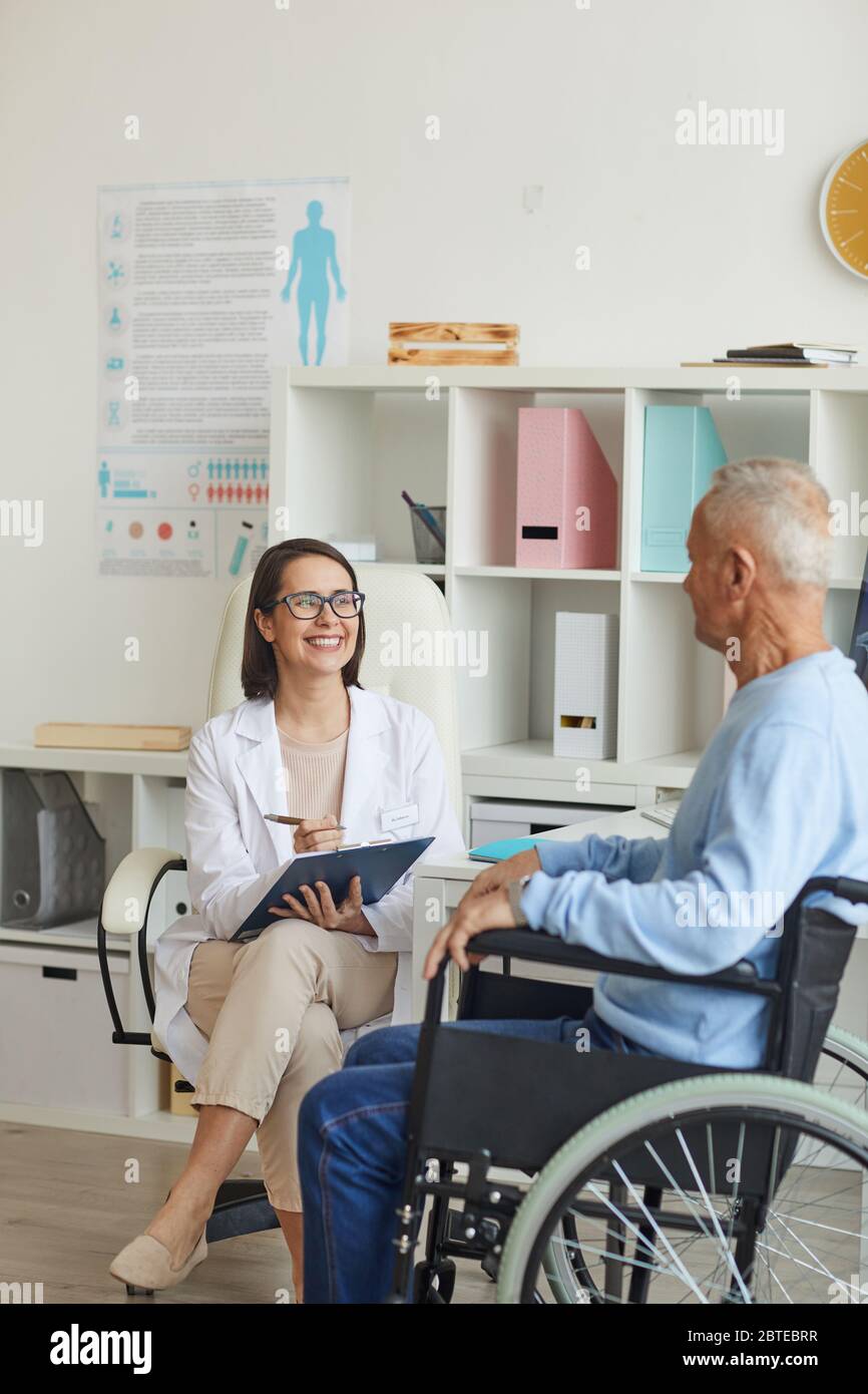 Portrait of smiling female doctor consulting handicapped senior man in ...