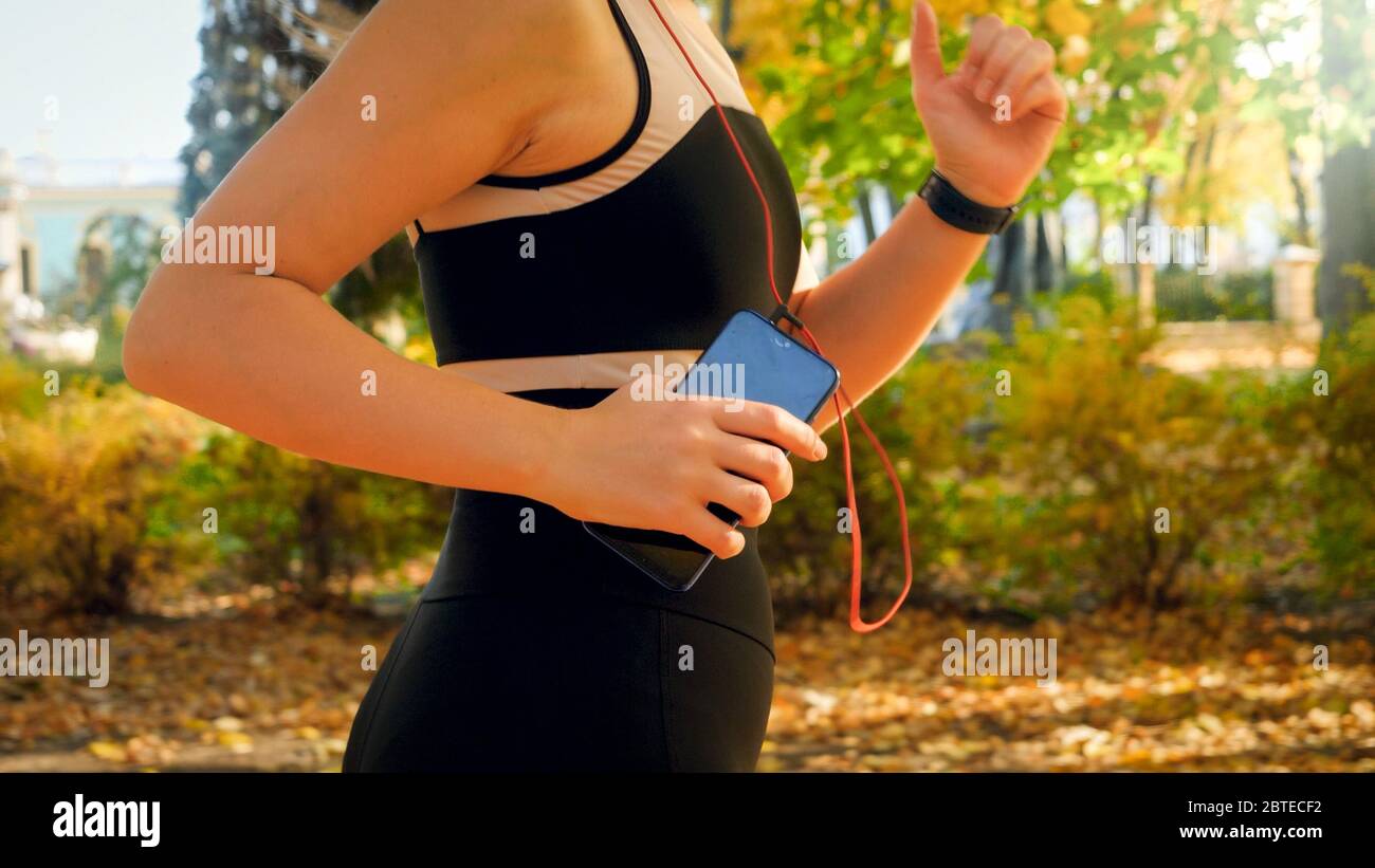 Closeup photo of young woman holding smartphone in hand while running ...