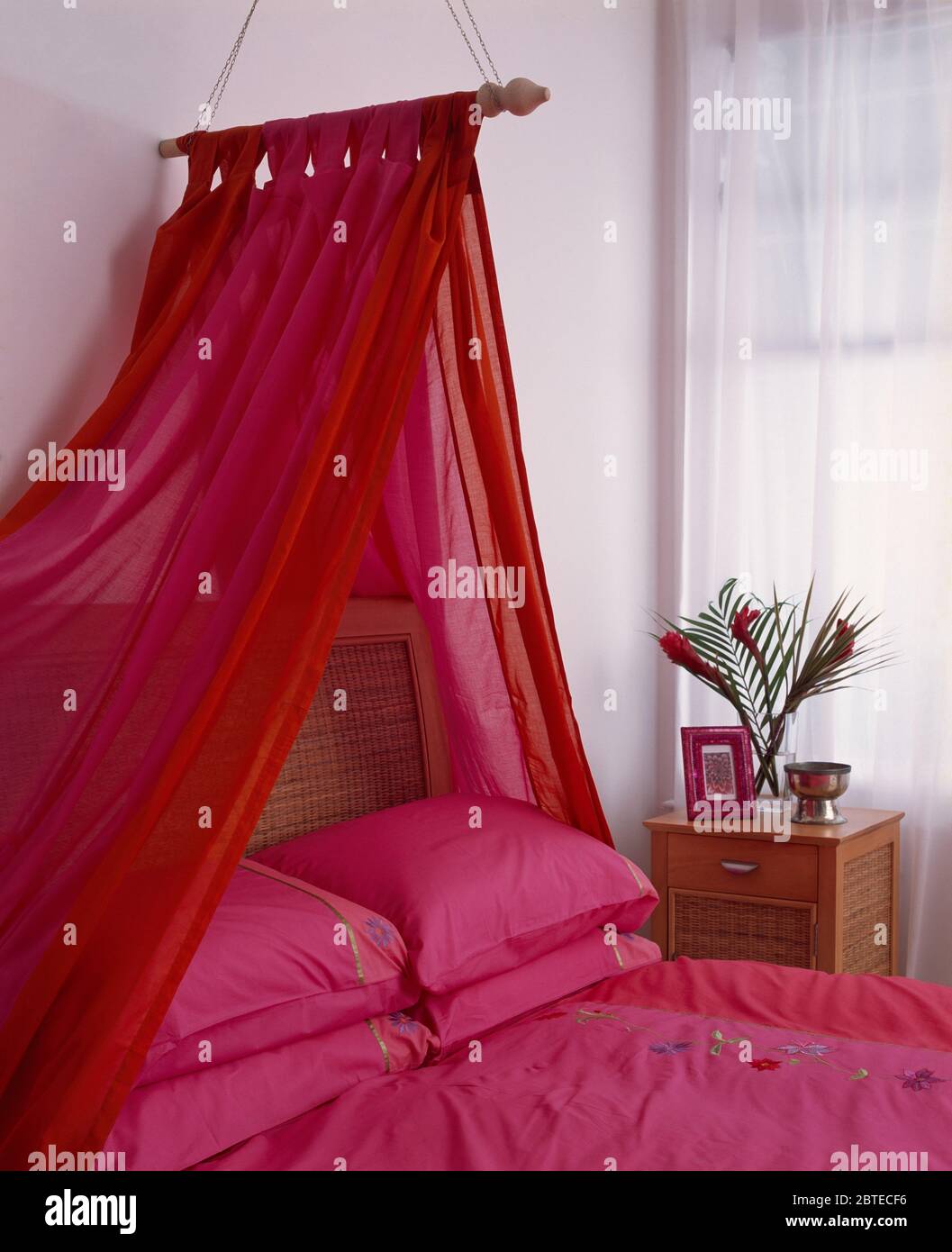 Bright pink and red voile drapes above bed with pink pillows Stock ...