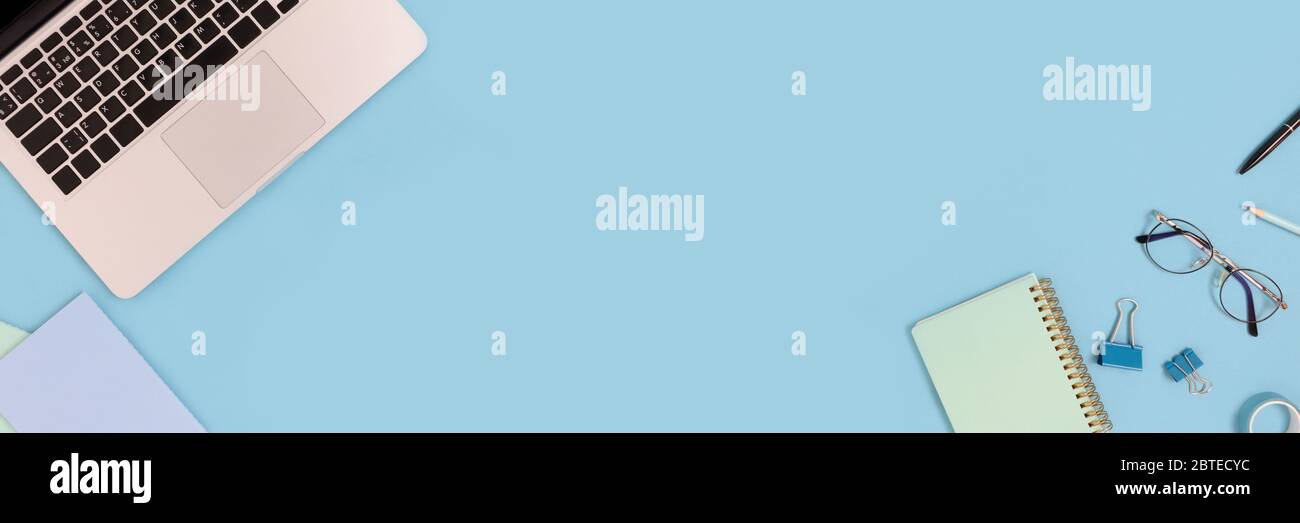 Top view of laptop and stationery on a blue pastel background ...