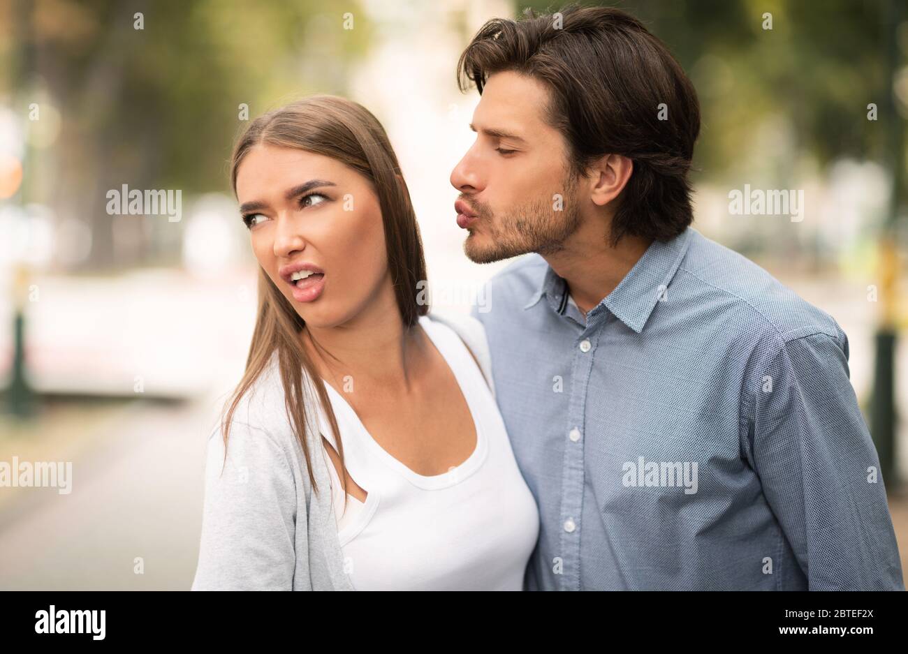 Disgusted Woman Rejecting To Kiss Man Walking Outdoors In Park Stock ...