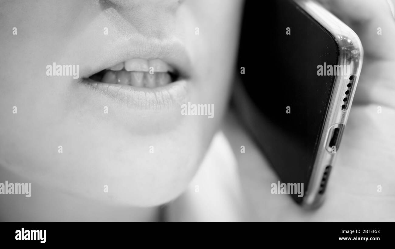 Black and white closeup photo of female mouth and lips talking by phone ...