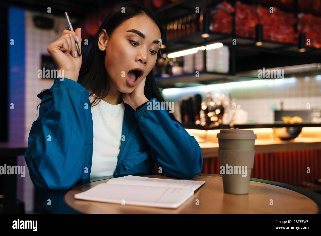 Photo of excited asian woman making notes in planner and expressing ...