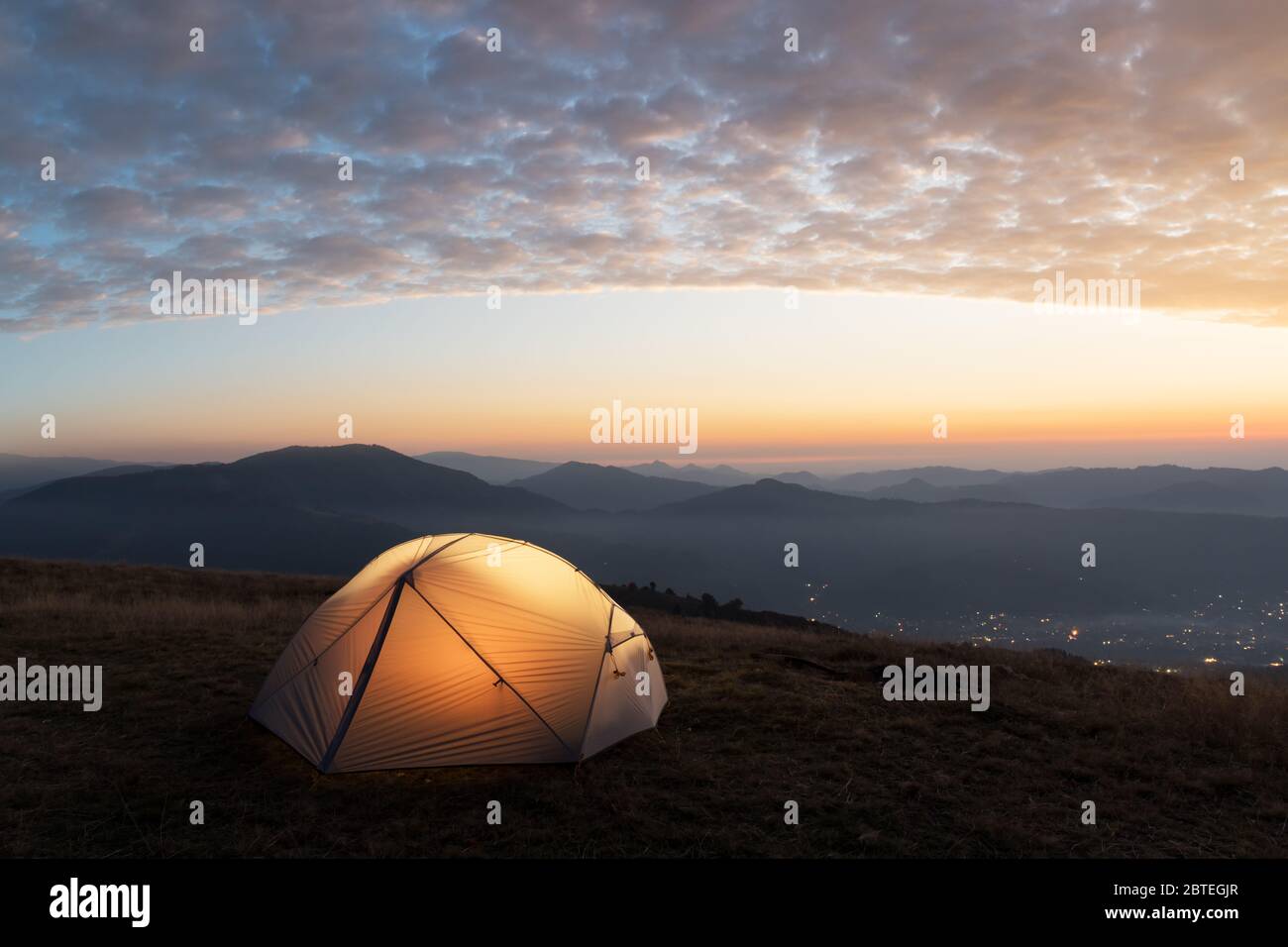 Grey tent lighted from the inside by a flashlight against the backdrop ...