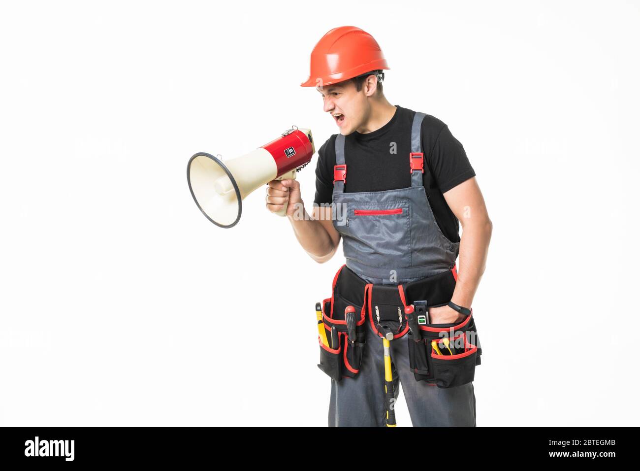 Full length of worker speaking into megaphone over white background ...