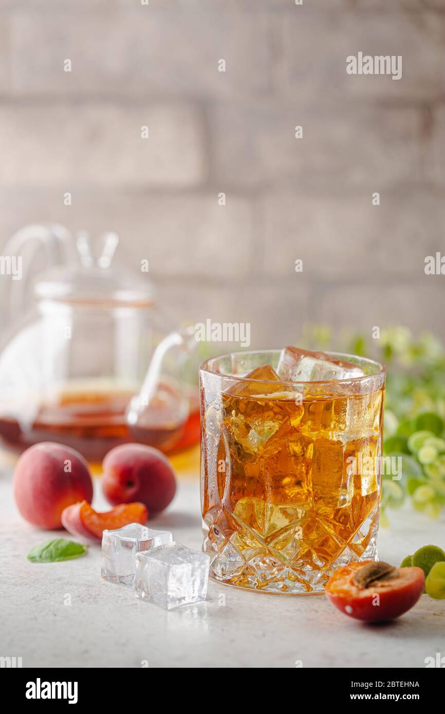 Glass of peach or apricot iced tea with fruit slices against white ...