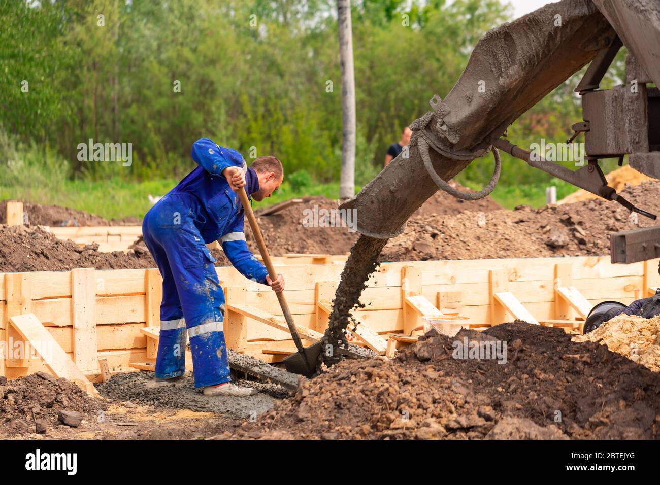 Construction worker laying cement or concrete into the foundation ...