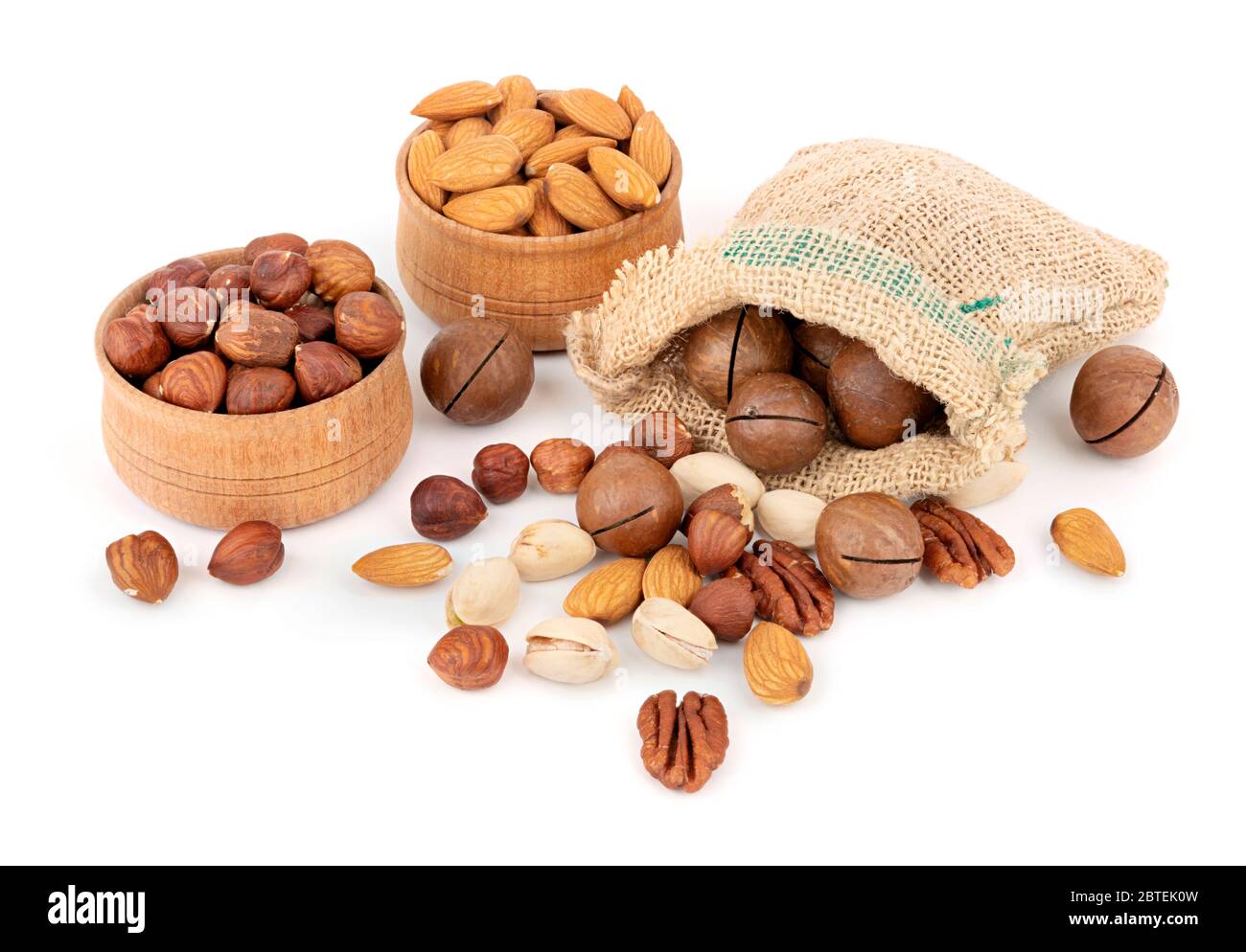Variety of nuts in sack and wooden bowls on white background. Vegan ...